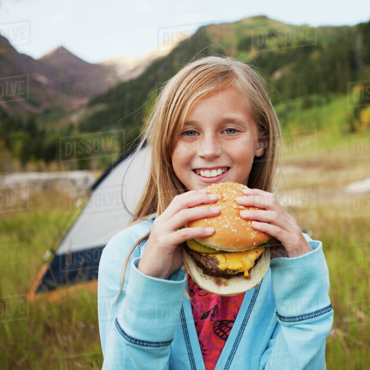Caucasian girl eating cheeseburger at campsite - Royalty-free Stock ...