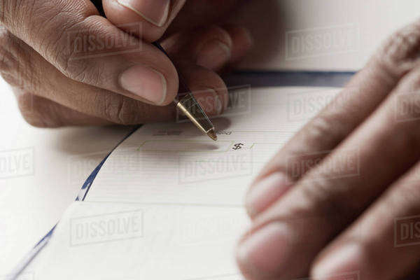 Mixed race man writing a check - Stock Photo - Dissolve