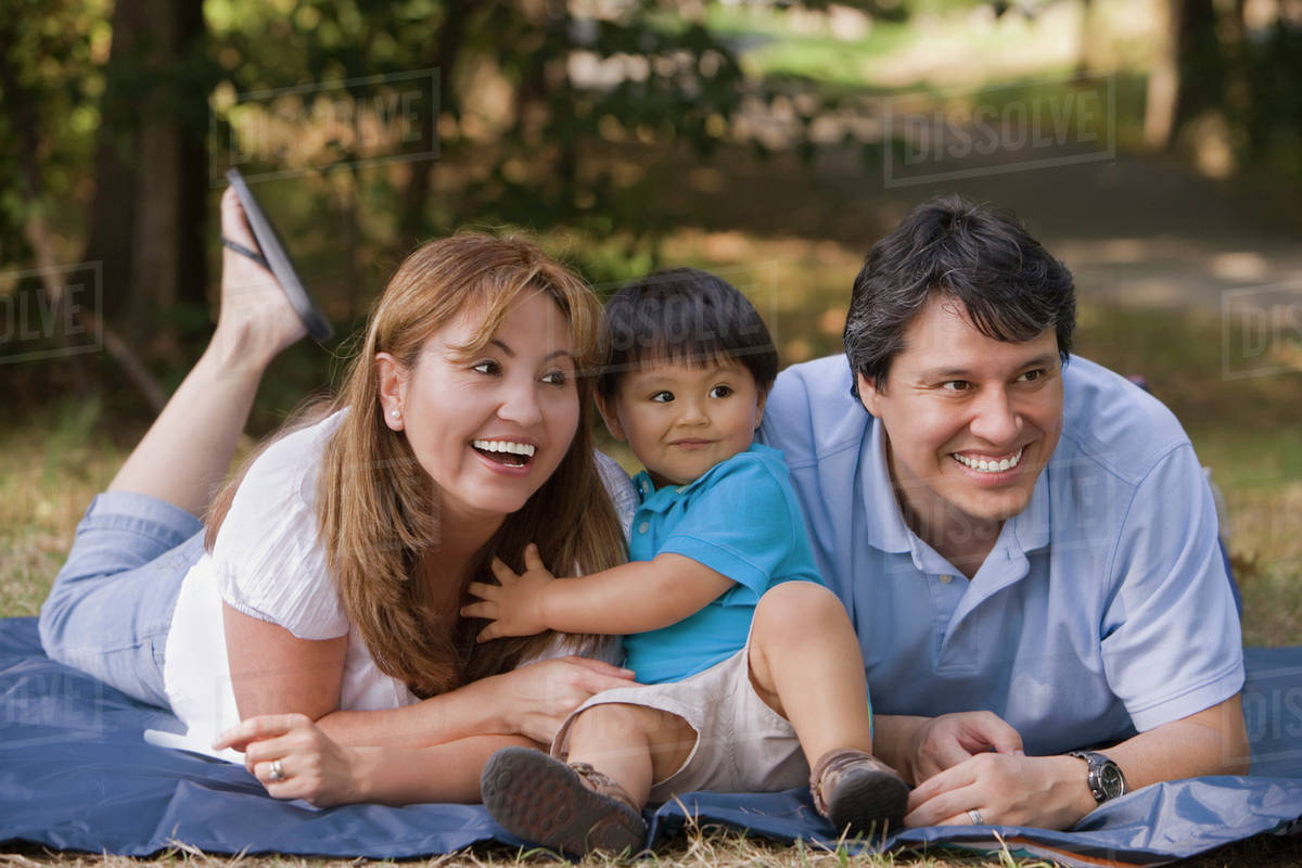 Hispanic parents enjoying park together - Stock Photo - Dissolve