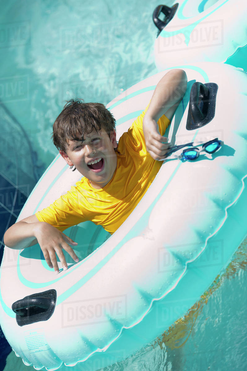 Hispanic boy floating on raft in swimming pool - Stock Photo - Dissolve