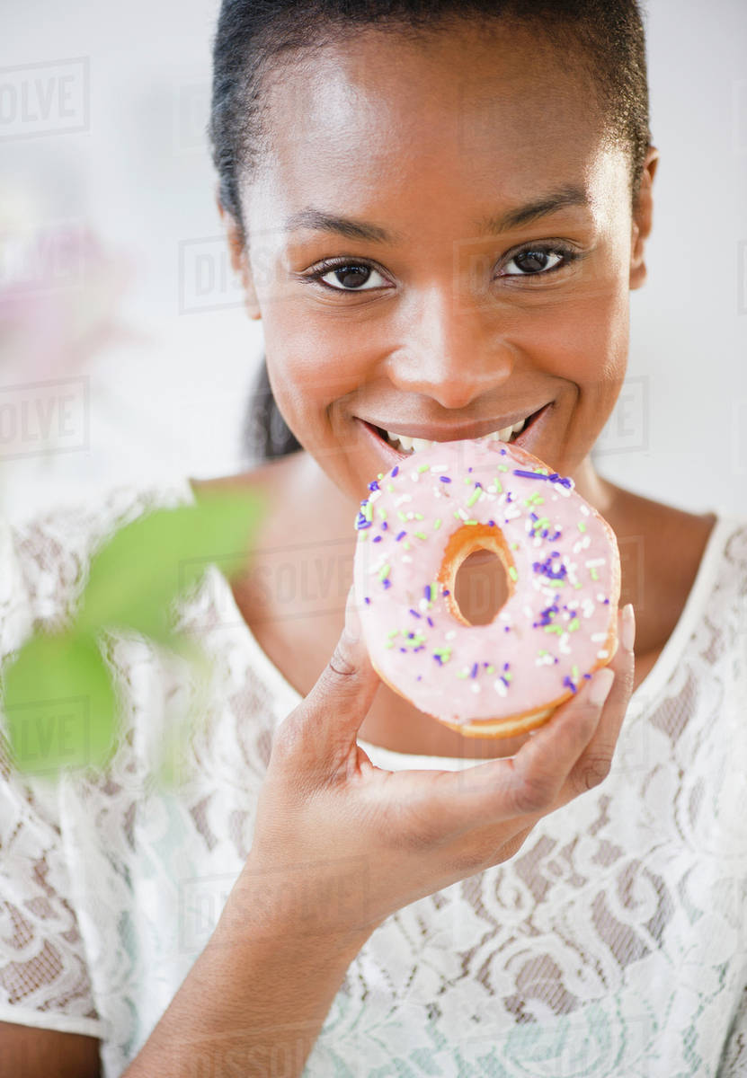 Black woman eating donut - Royalty-free Stock Photo | Dissolve