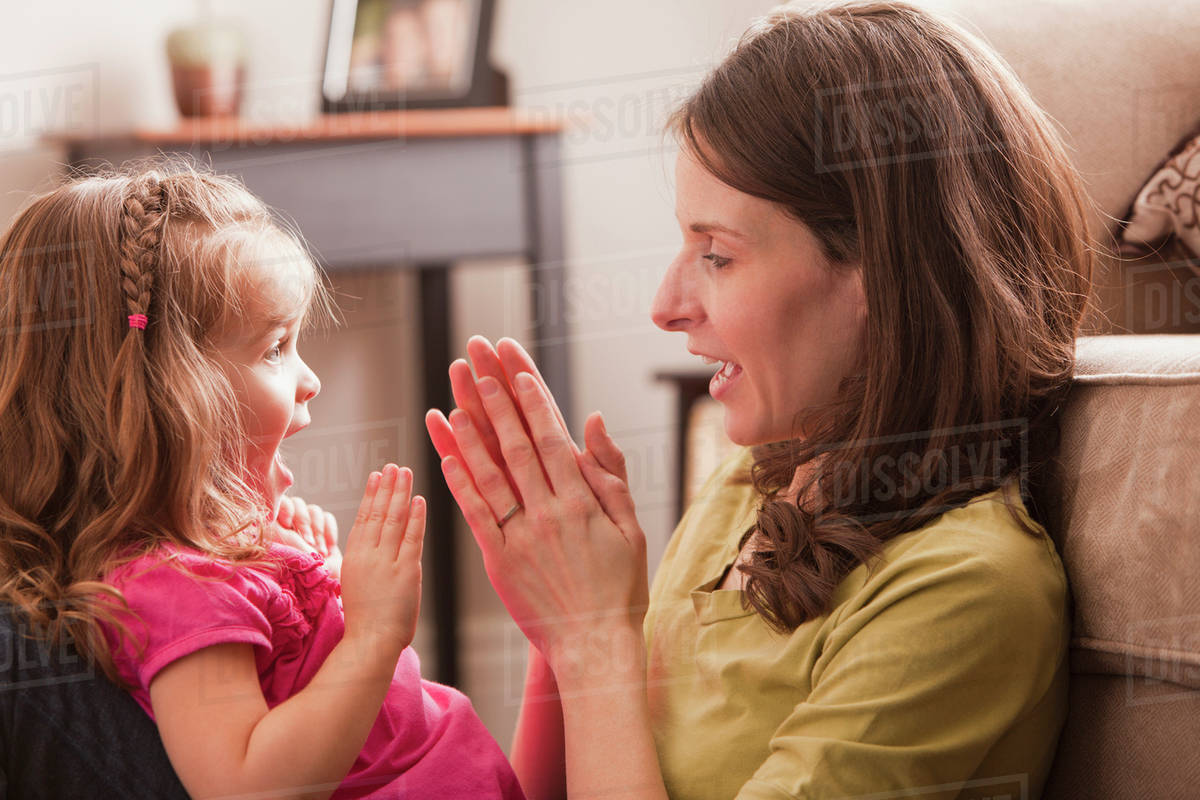 Caucasian mother and daughter playing clapping game - Royalty-free Stock Photo | Dissolve