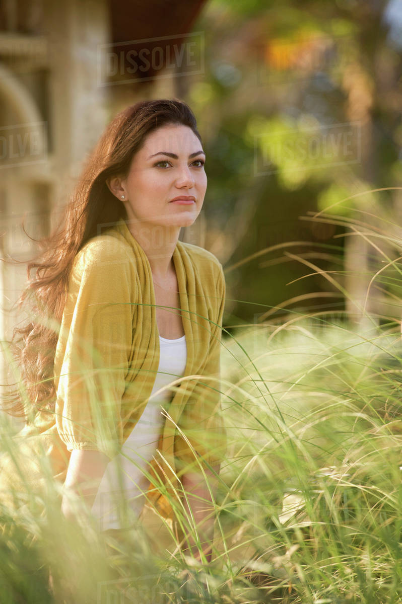 Serious Hispanic woman standing outdoors - Stock Photo - Dissolve