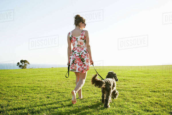 Caucasian woman walking dog in field - Royalty-free Stock Photo | Dissolve