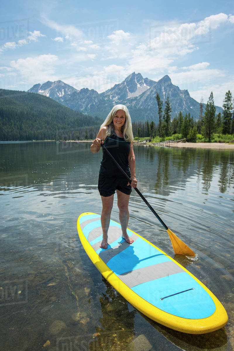Caucasian woman standing on paddle board in lake - Royalty-free Stock ...