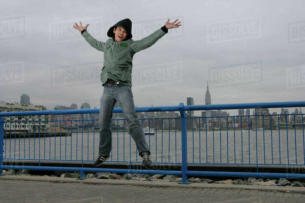 Happy Chinese man jumping on bridge - Stock Photo - Dissolve