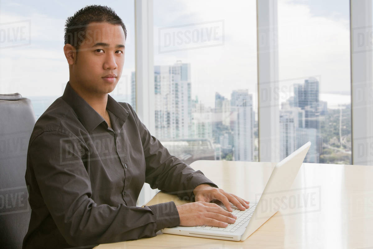 Chinese man using laptop in office - Royalty-free Stock Photo | Dissolve