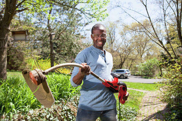 Black man holding weed trimmer - Royalty-free Stock Photo | Dissolve