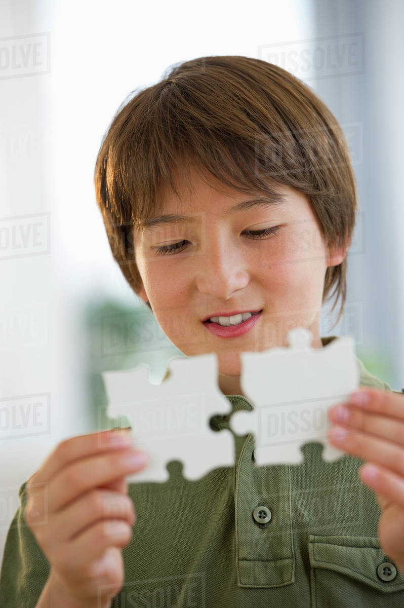 Mixed race boy connecting jigsaw pieces - Royalty-free Stock Photo ...