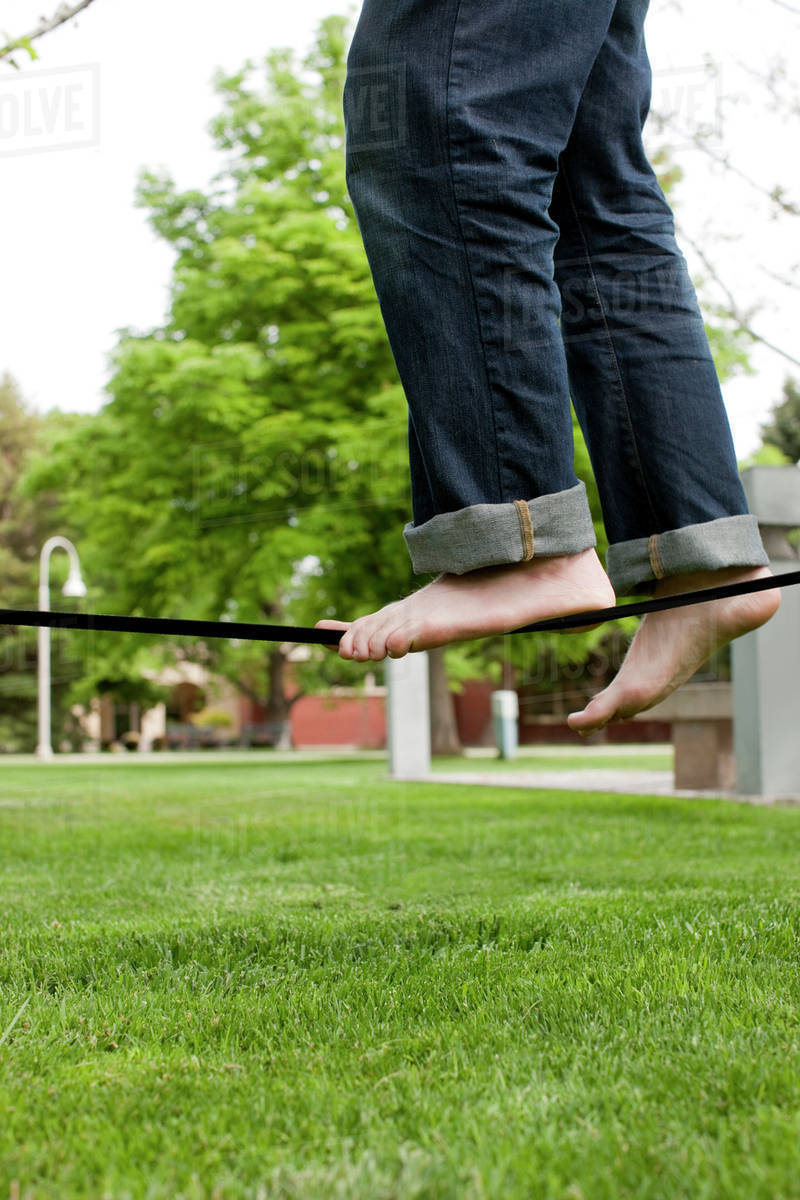 Caucasian man balancing on rope in park - Stock Photo - Dissolve