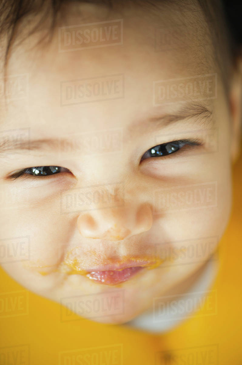 Grinning mixed race baby with messy face - Stock Photo - Dissolve