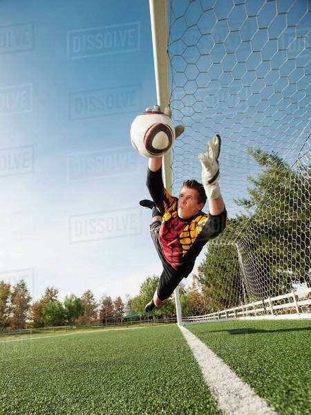 Mixed race goalkeeper in mid-air protecting goal - Royalty-free Stock ...