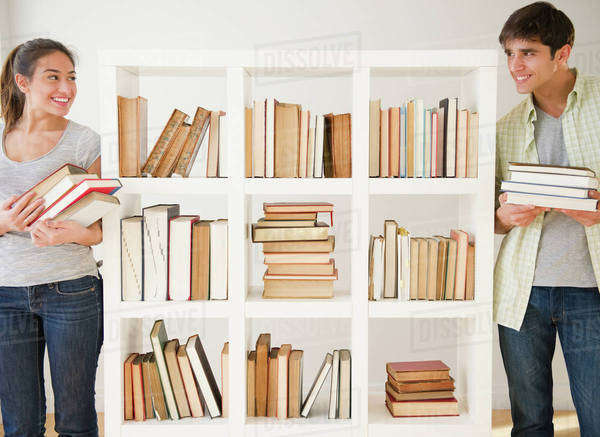 Couple with books standing near bookshelf - Royalty-free Stock Photo ...