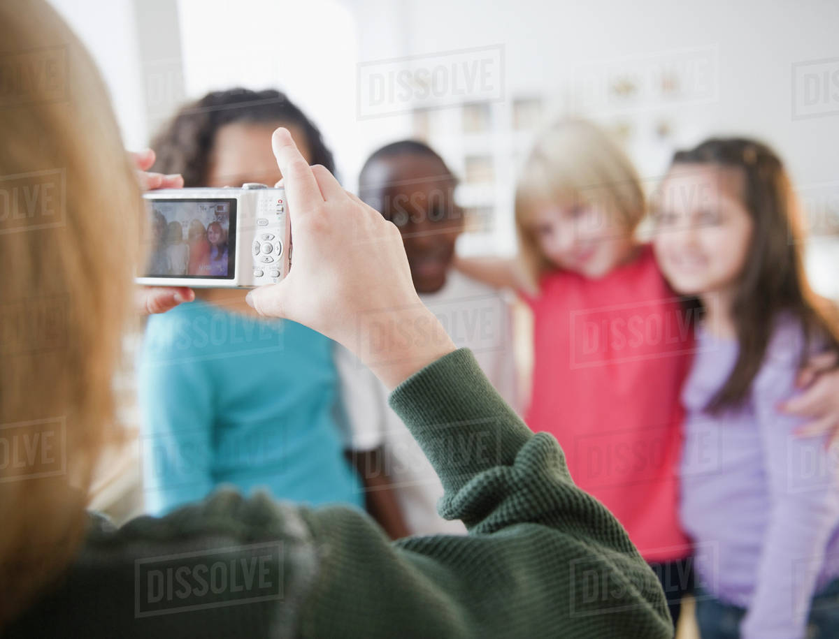 Girl taking photograph of friends with digital camera - Royalty-free ...
