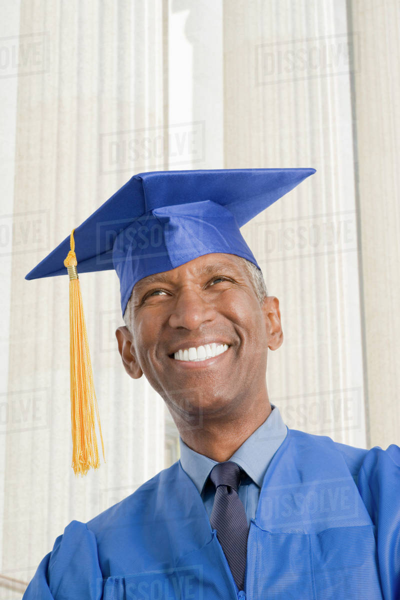 Mixed race man in graduation cap and gown - Stock Photo - Dissolve