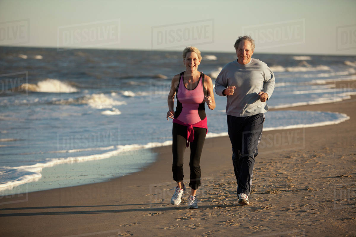 Couple running together on beach - Royalty-free Stock Photo | Dissolve