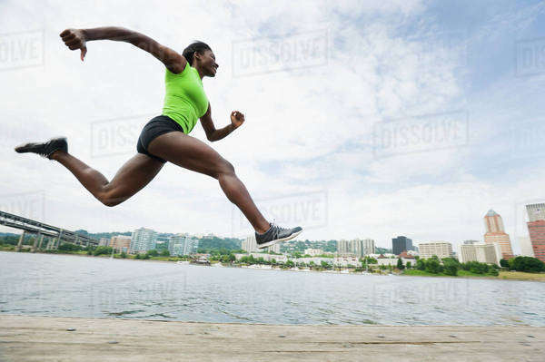 African woman leaping next to river - Royalty-free Stock Photo | Dissolve