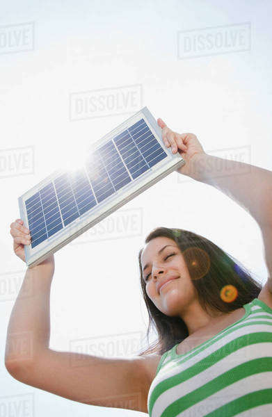 Mixed race woman holding solar panel - Royalty-free Stock Photo | Dissolve