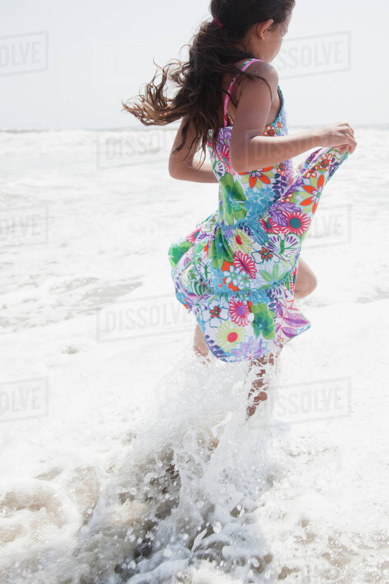 Hispanic girl wading on ocean - Royalty-free Stock Photo | Dissolve
