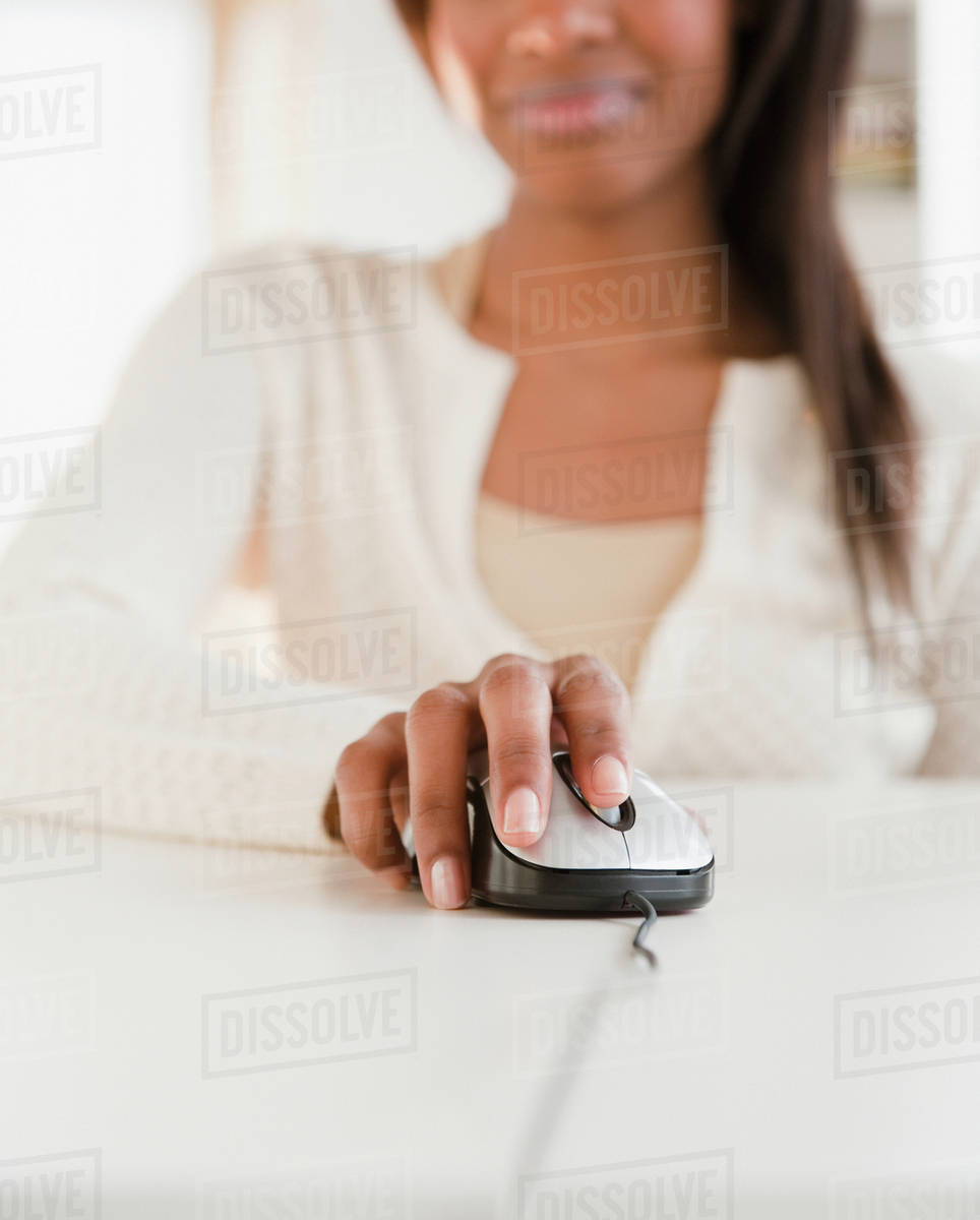 Mixed race woman using computer mouse - Royalty-free Stock Photo | Dissolve