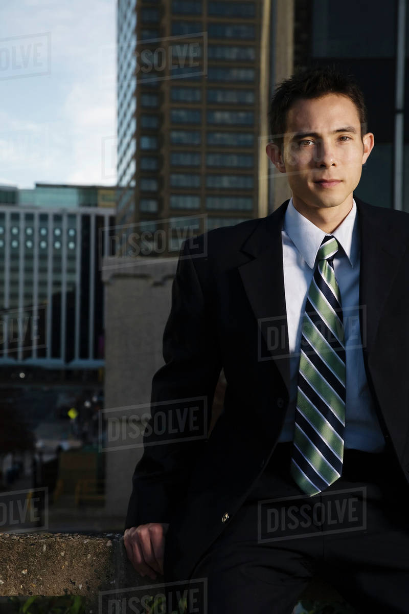 Mixed race businessman sitting on urban rooftop - Royalty-free Stock ...