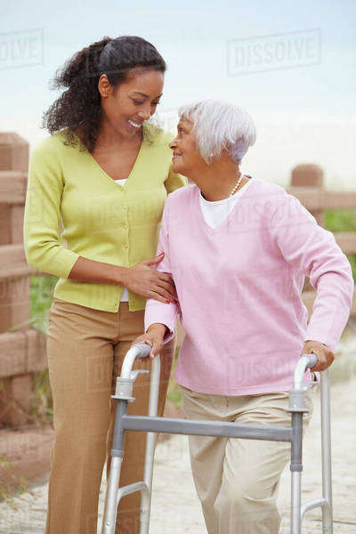 African American woman helping mother use walker - Stock Photo - Dissolve