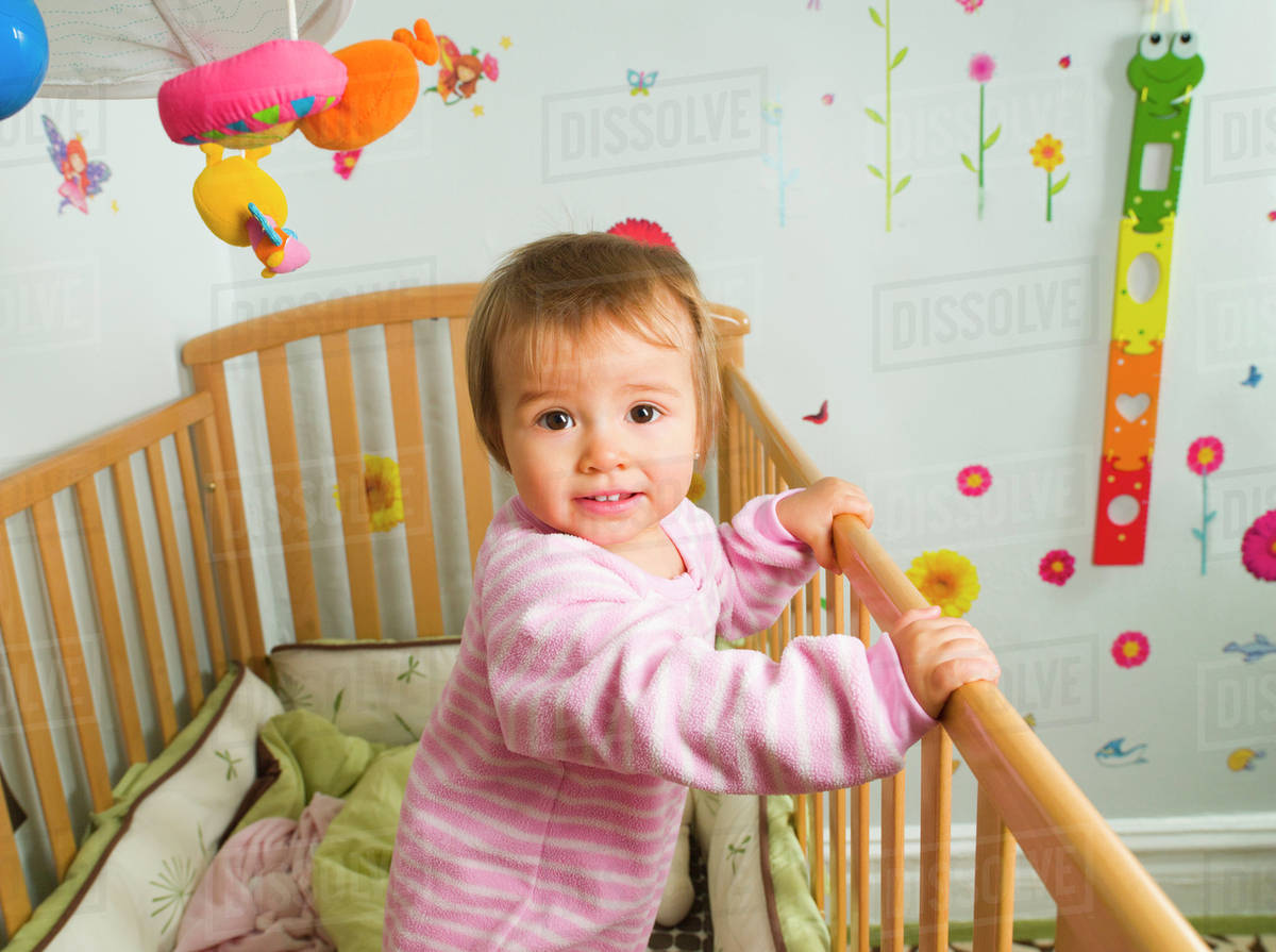 Mixed race baby girl standing in crib - Royalty-free Stock Photo | Dissolve