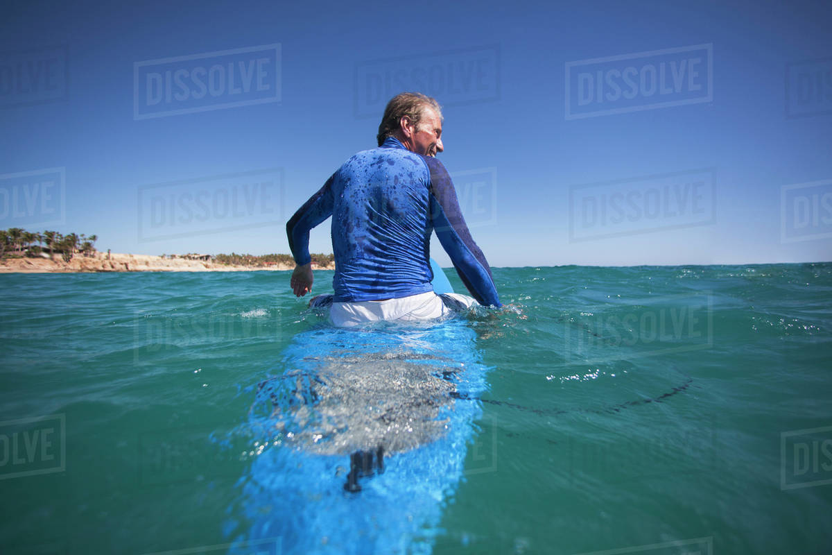 Caucasian man floating on surfboard - Stock Photo - Dissolve