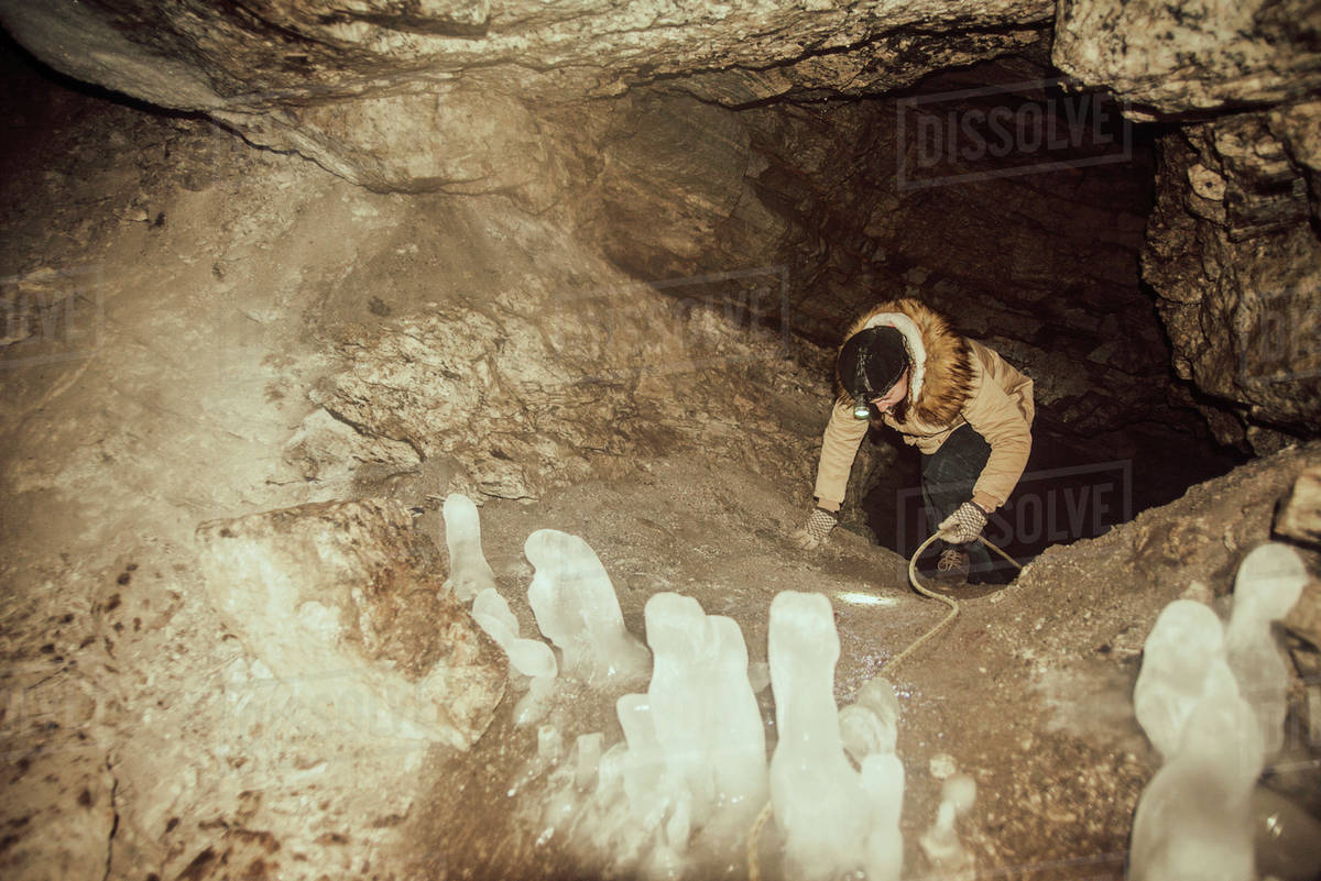 Caucasian hiker climbing in cave - Stock Photo - Dissolve