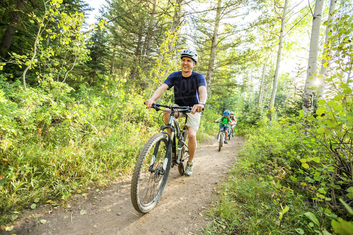 Caucasian father and children riding mountain bikes - Royalty-free ...