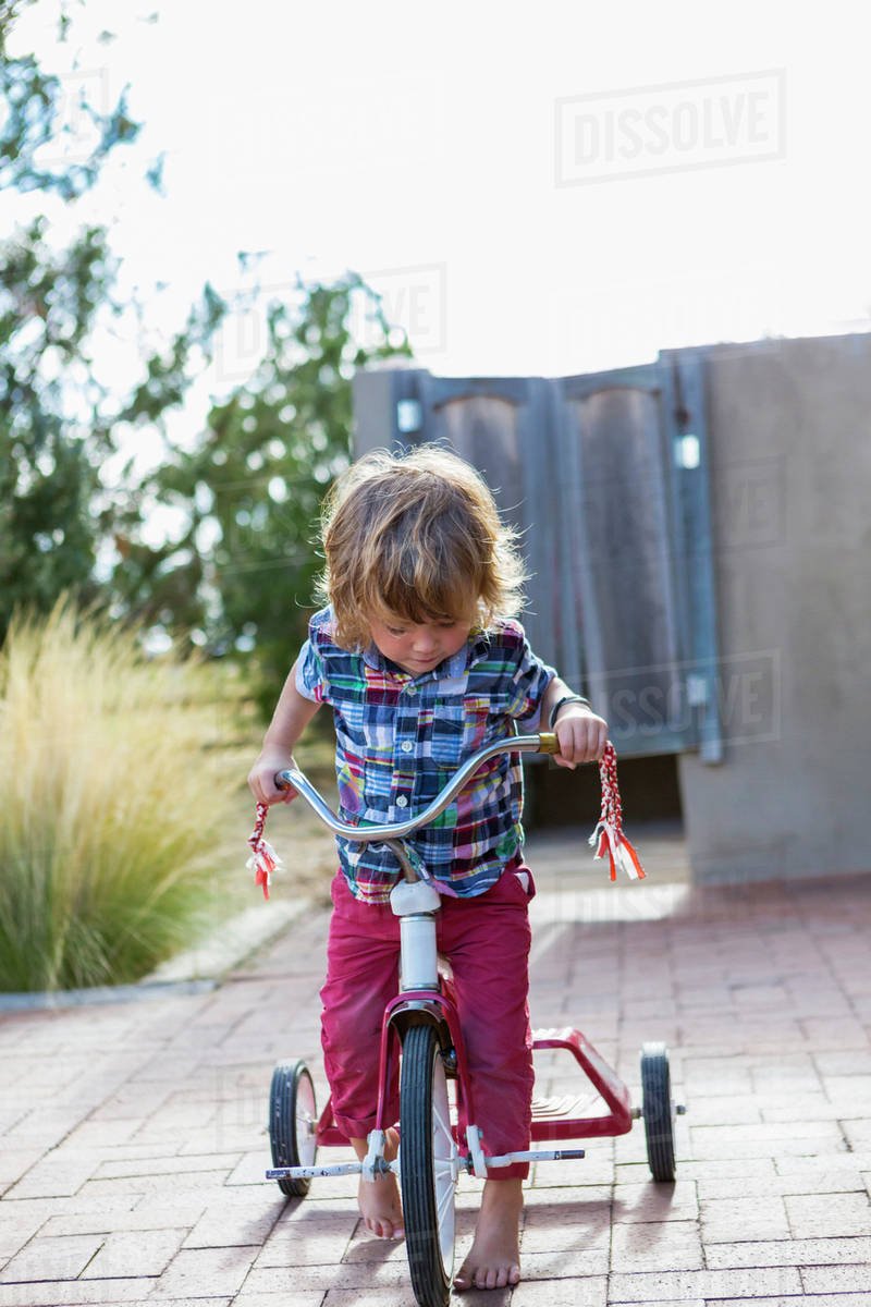 Caucasian boy riding tricycle in backyard - Royalty-free Stock Photo ...