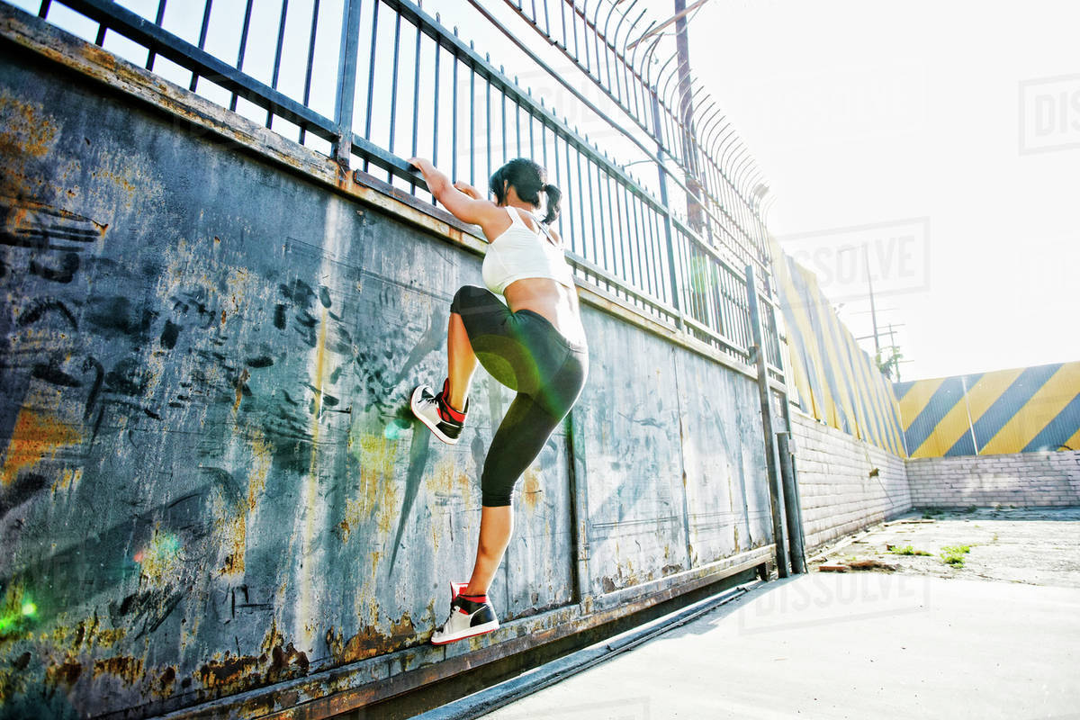 Mixed race woman climbing gate - Royalty-free Stock Photo | Dissolve