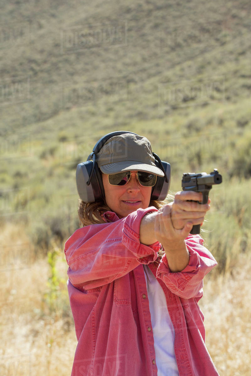 Caucasian woman aiming gun outdoors - Royalty-free Stock Photo | Dissolve