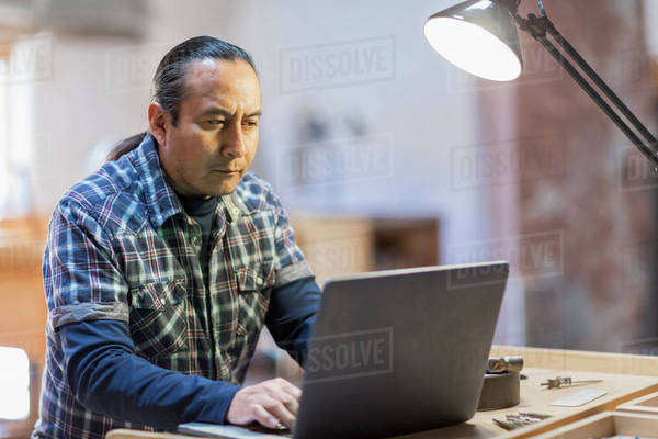Native American artist using laptop in studio - Stock Photo - Dissolve
