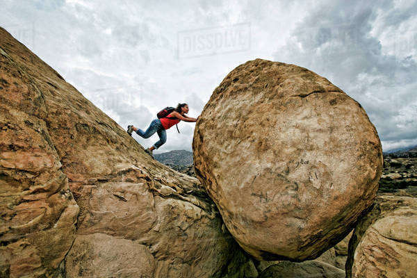 Hispanic woman pushing boulder on rocky hillside - Royalty-free Stock ...