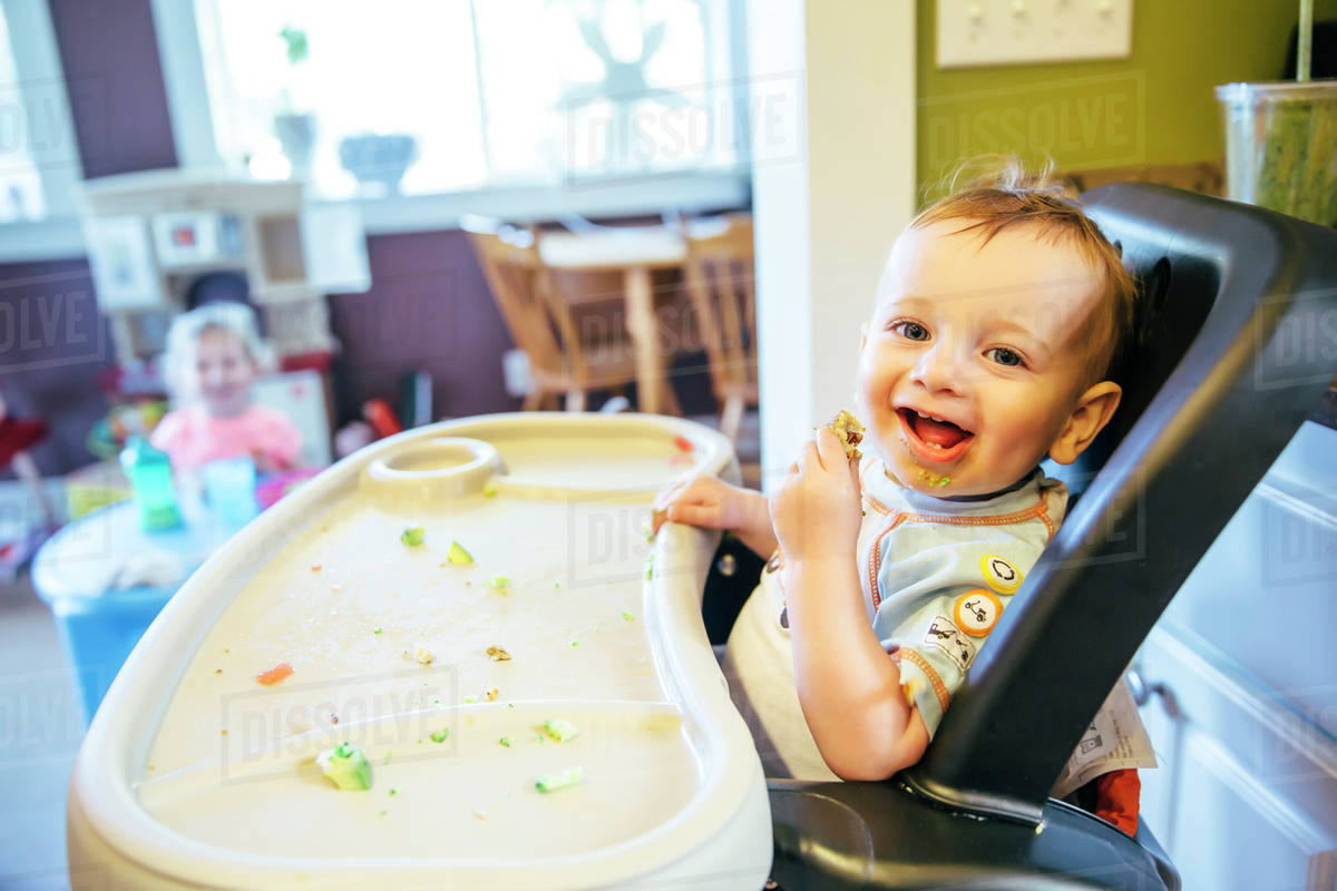 Caucasian boy eating in high chair - Royalty-free Stock Photo | Dissolve