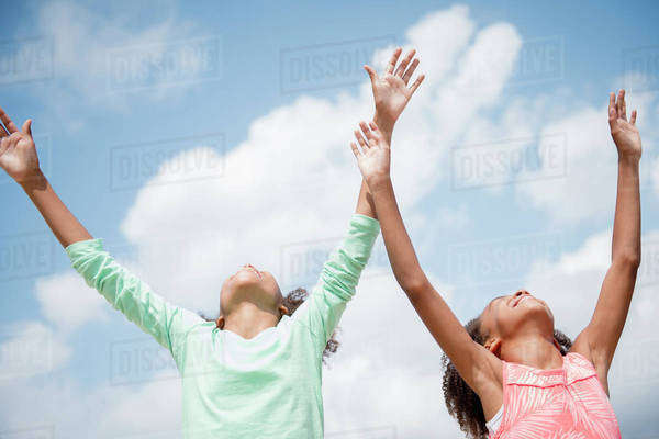 Mixed race sisters cheering in blue sky - Royalty-free Stock Photo ...