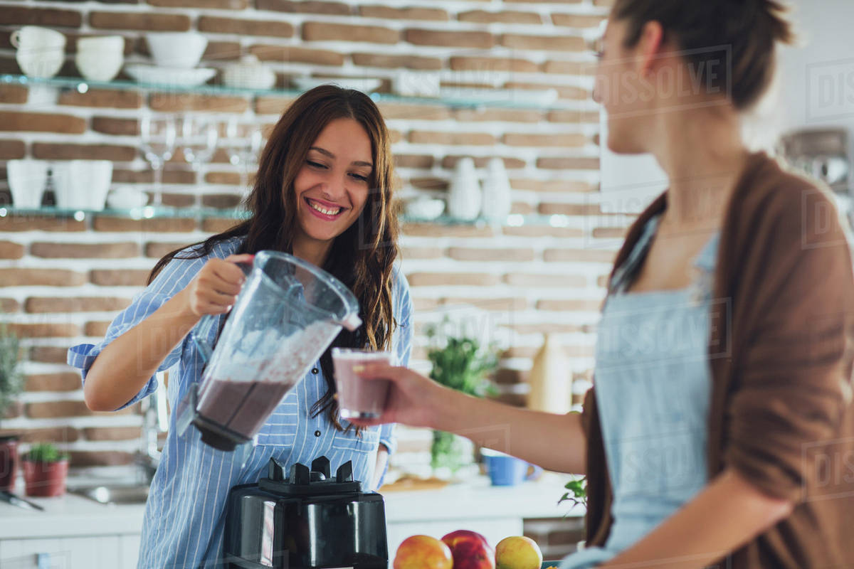 Caucasian women pouring smoothie in kitchen - Royalty-free Stock Photo ...