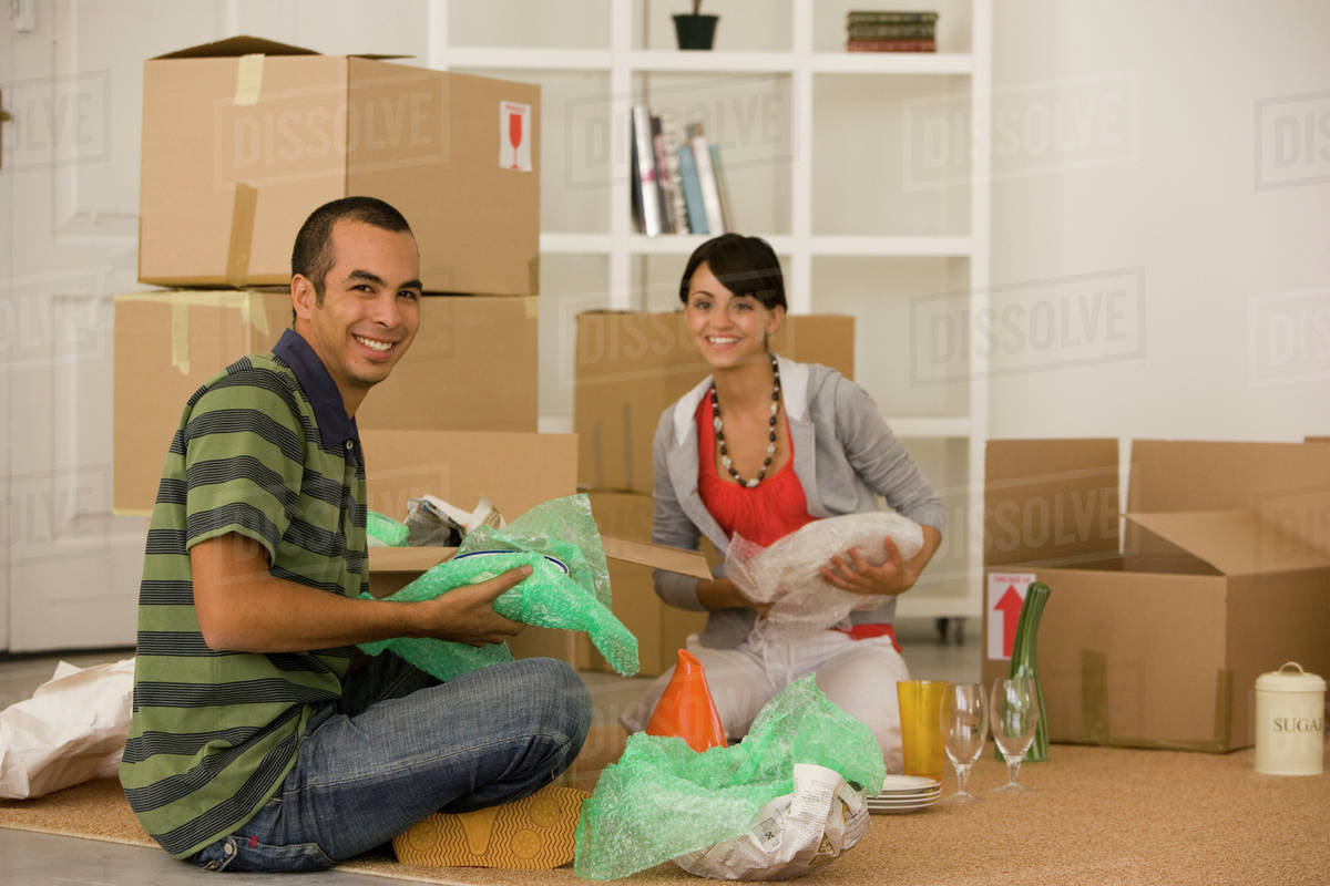 Young couple packing moving boxes - Stock Photo - Dissolve