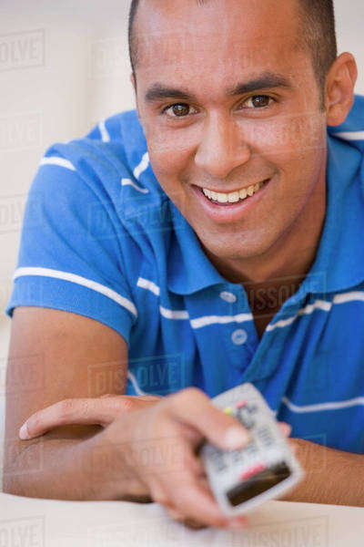 Young man pointing remote control - Stock Photo - Dissolve