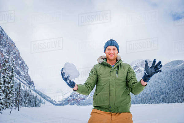 Caucasian man holding snowball near mountains, Lake Louise, Alberta ...