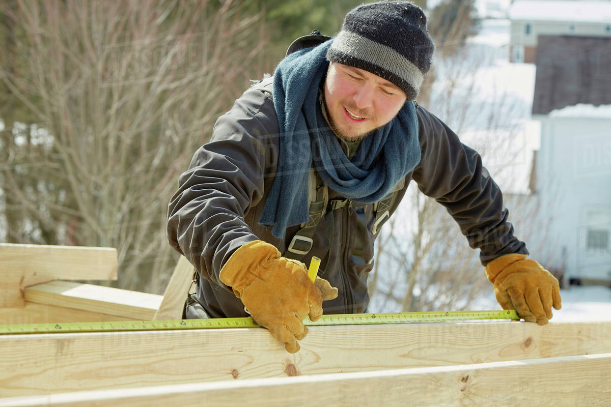 Caucasian carpenter measuring wood planks in winter - Stock Photo ...