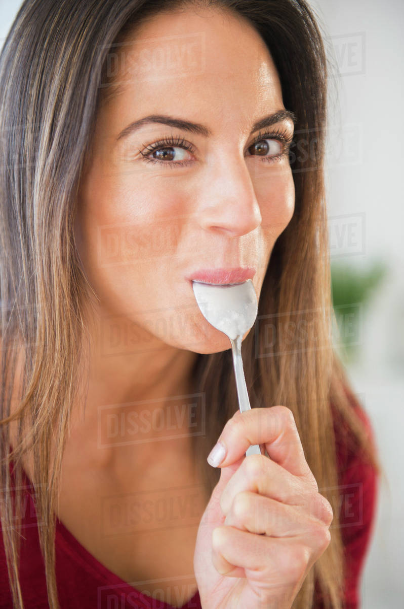 Smiling Caucasian woman licking spoon - Royalty-free Stock Photo | Dissolve