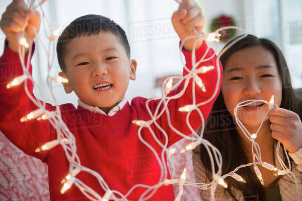 Asian children playing with Christmas string lights - Royalty-free ...