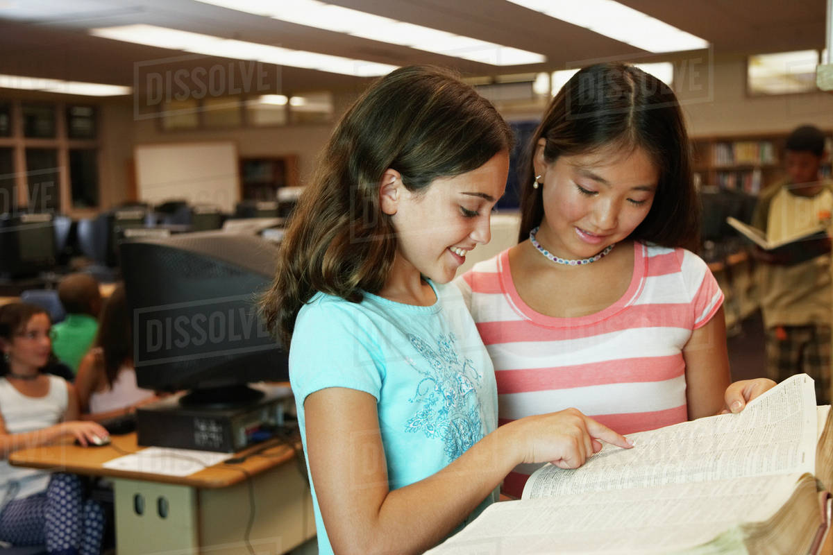 Multi-ethnic girls reading library dictionary - Royalty-free Stock ...