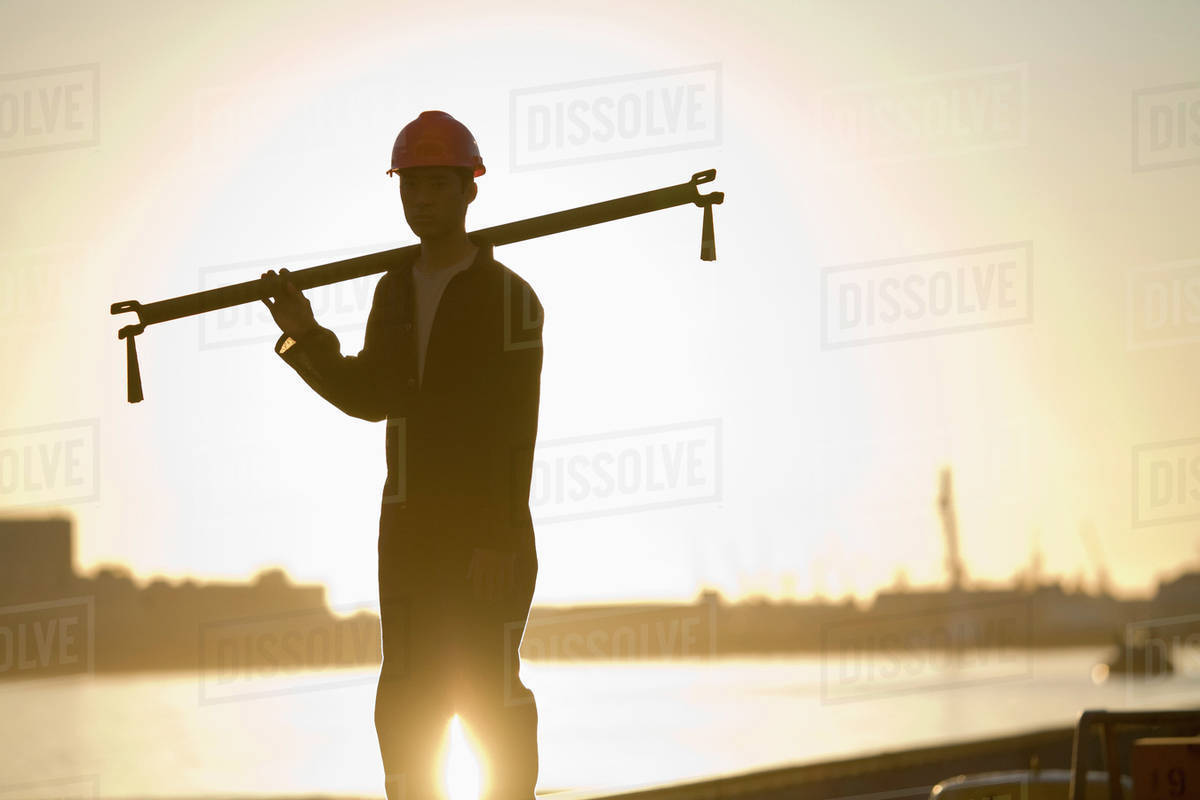 Asian male dock worker holding pipe - Royalty-free Stock Photo | Dissolve