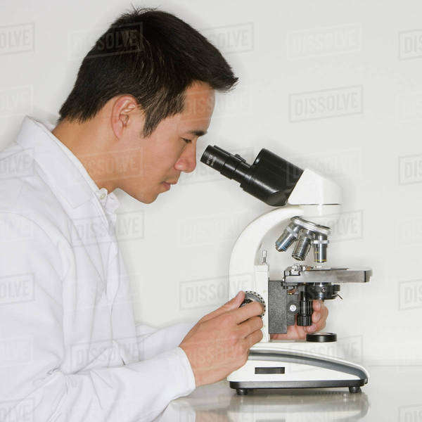 Asian male scientist looking into microscope - Stock Photo - Dissolve