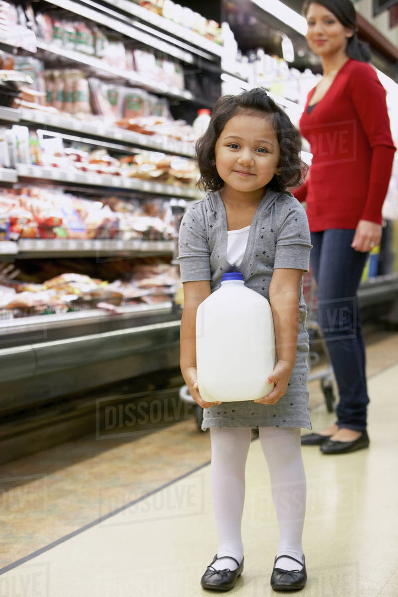 Indian girl carrying milk in grocery store - Stock Photo - Dissolve