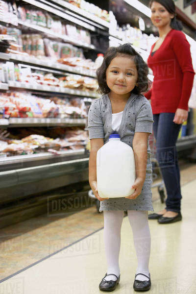 Indian girl carrying milk in grocery store - Stock Photo - Dissolve