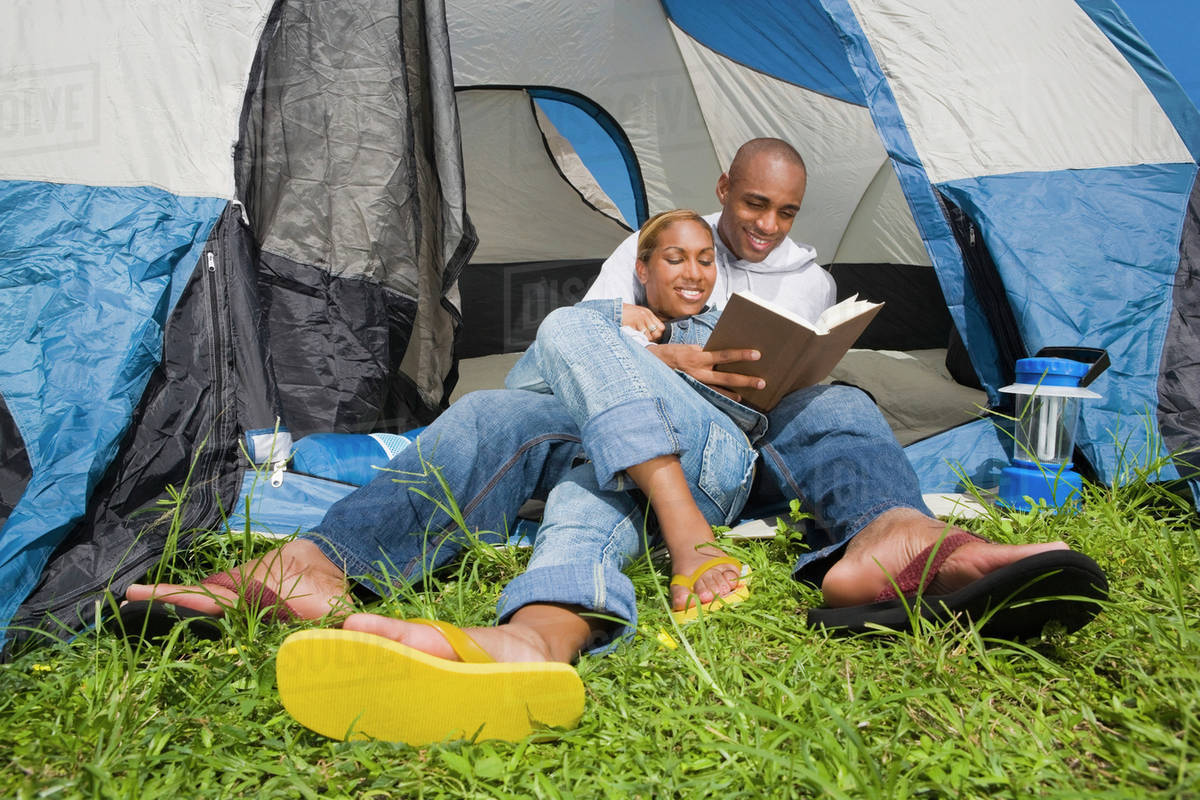 African couple reading at campsite - Royalty-free Stock Photo | Dissolve